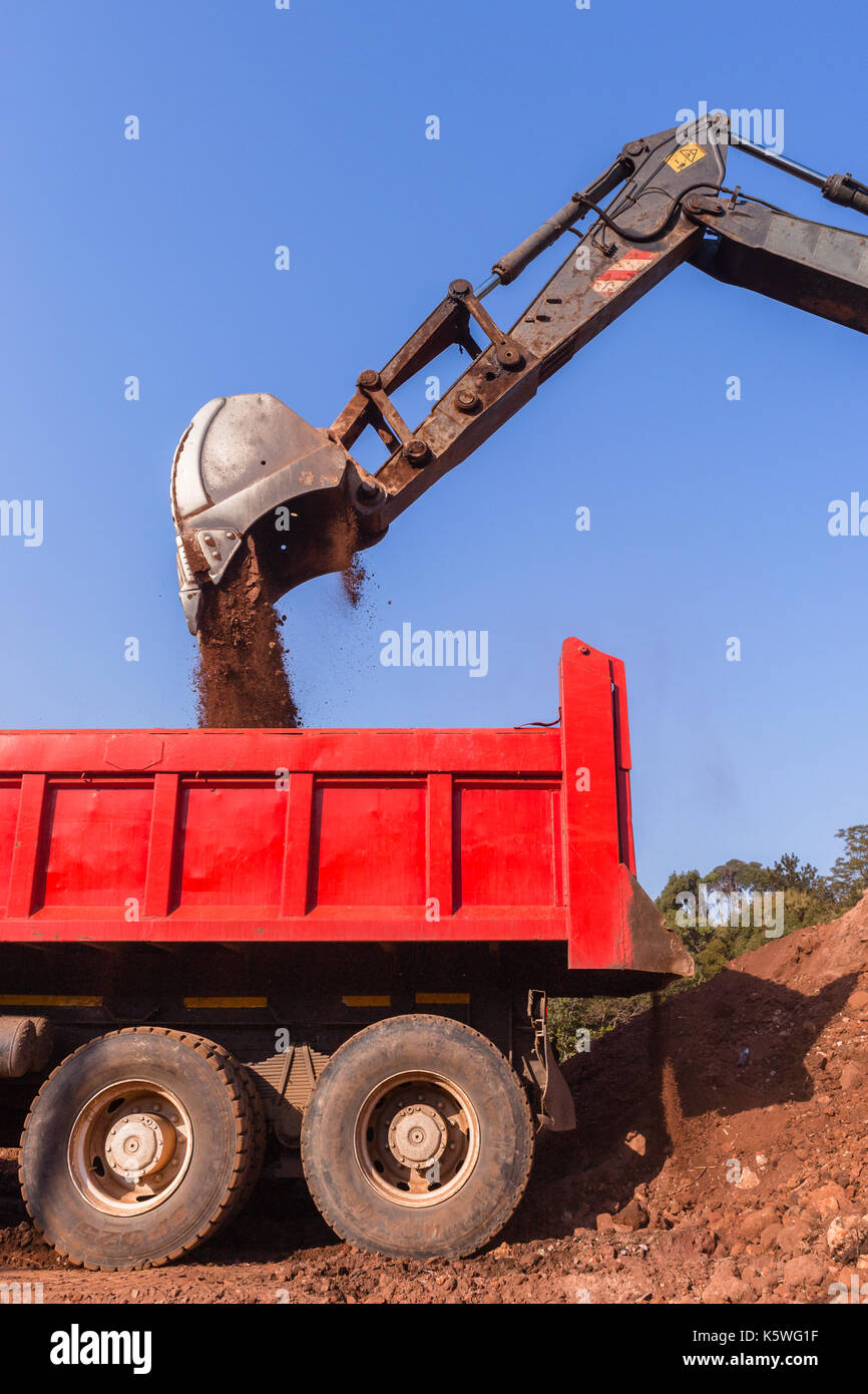 Excavator earthworks machine loading soil into truck bin closeup ...
