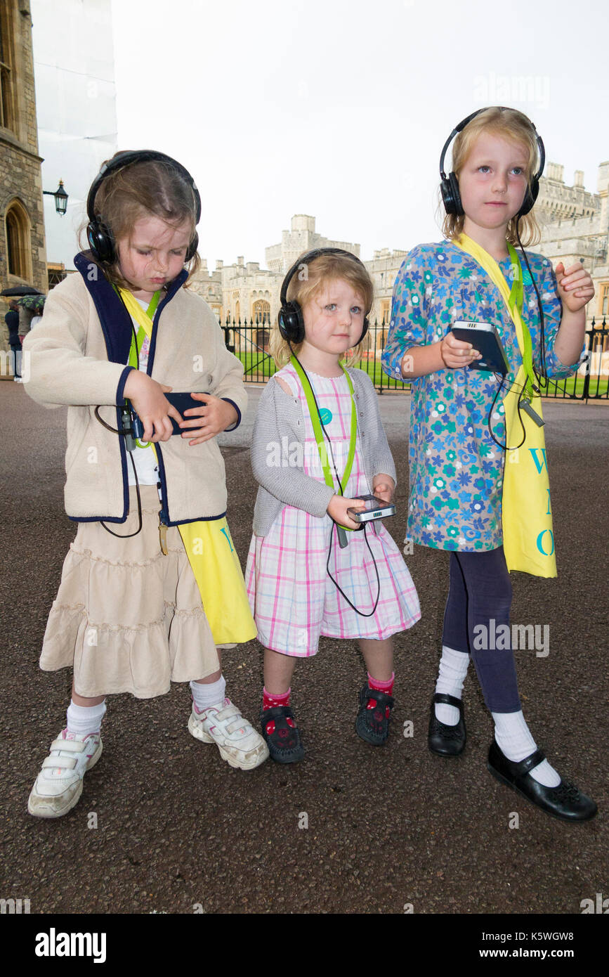 Three sisters /children /kid /kids on holiday listen to an audio guide ...