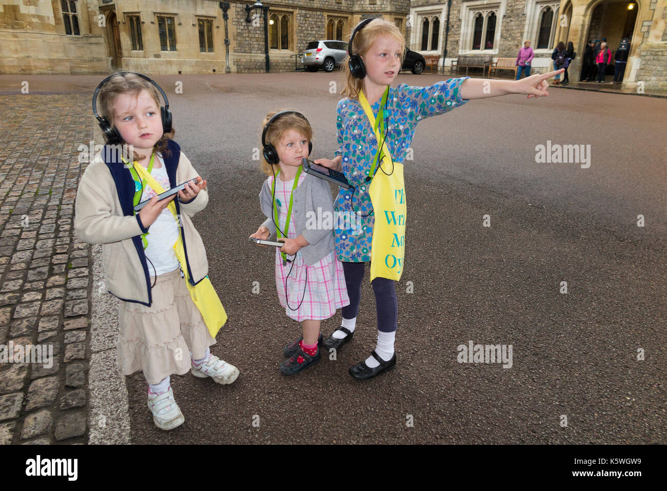Three sisters /children /kid /kids on holiday listen to an audio guide ...