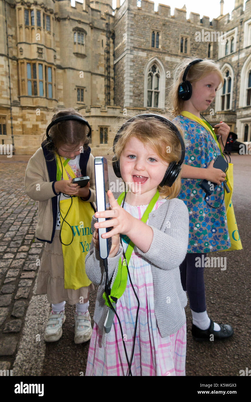 Three sisters /children /kid /kids on holiday listen to an audio guide ...