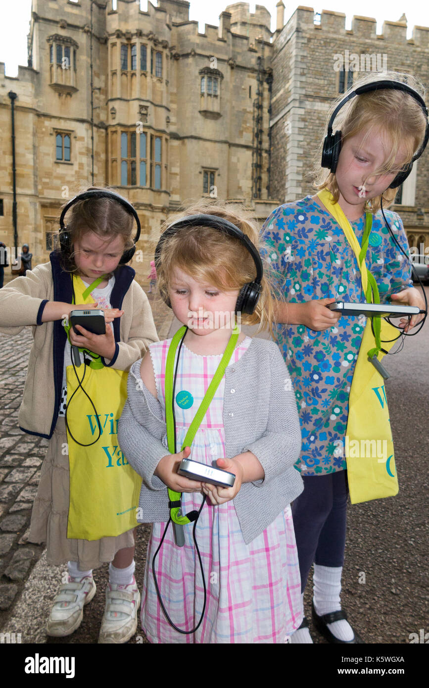 Three sisters /children /kid /kids on holiday listen to an audio guide ...