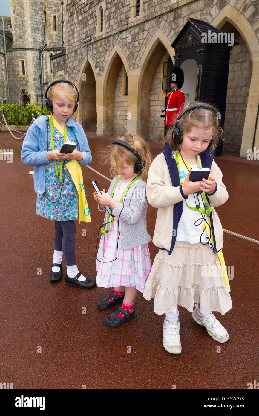 Three sisters /children /kid /kids on holiday listen to an audio guide ...