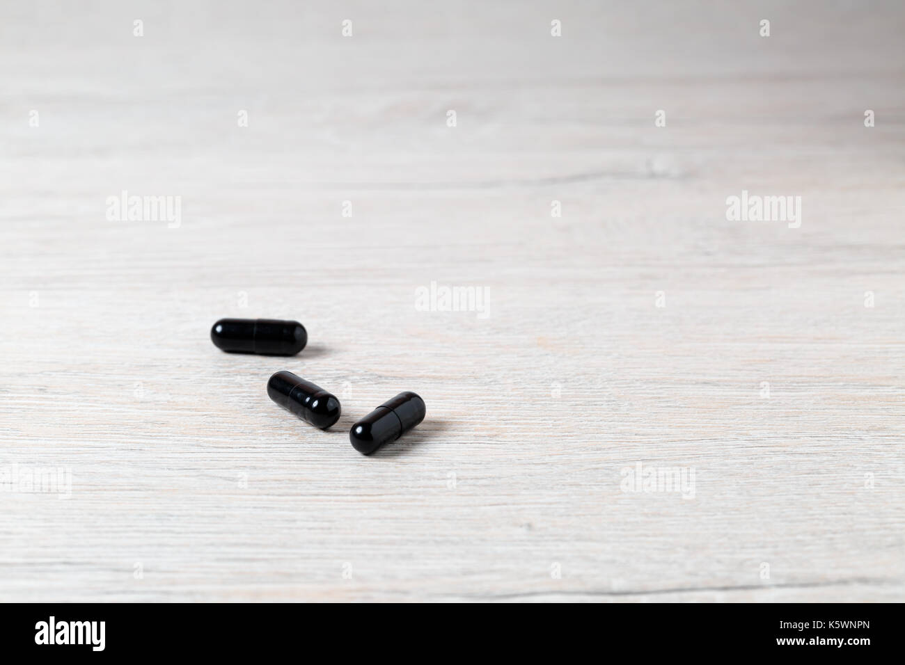 Three black medicine capsules on bright table Stock Photo - Alamy