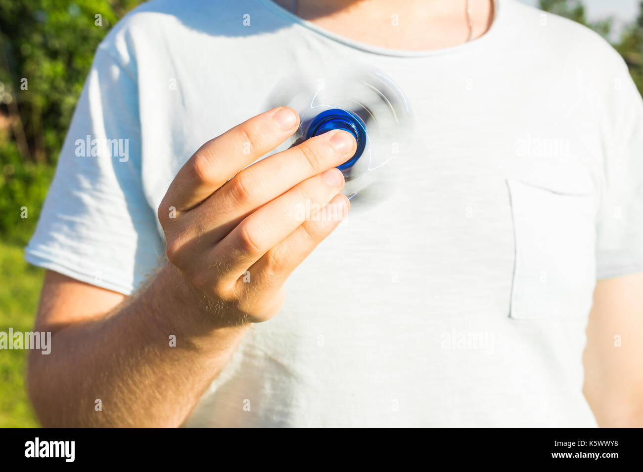 Man playing with a blue spinner fidget toy, close up Stock Photo - Alamy