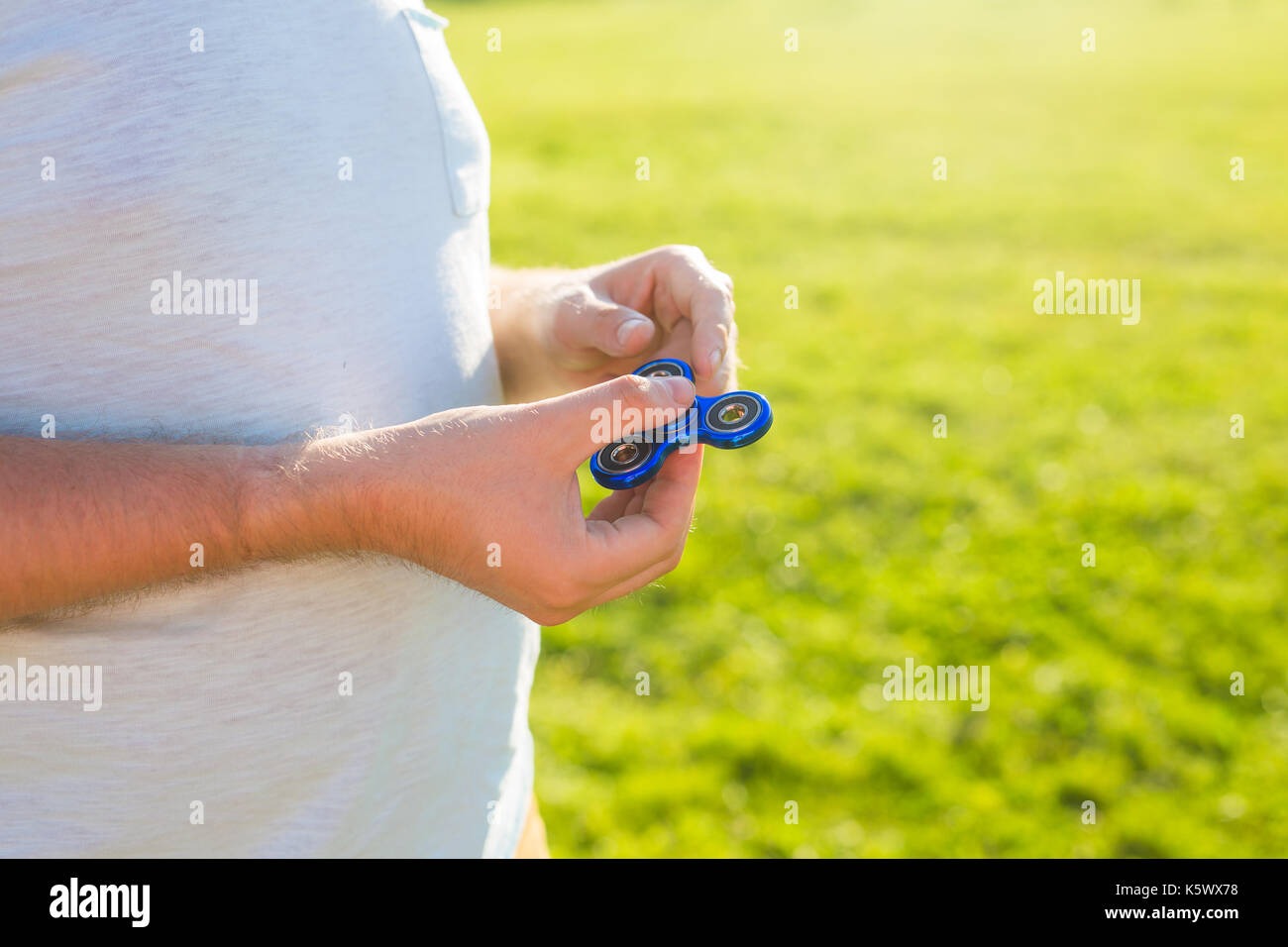 Man playing with a blue spinner fidget toy, close up Stock Photo - Alamy