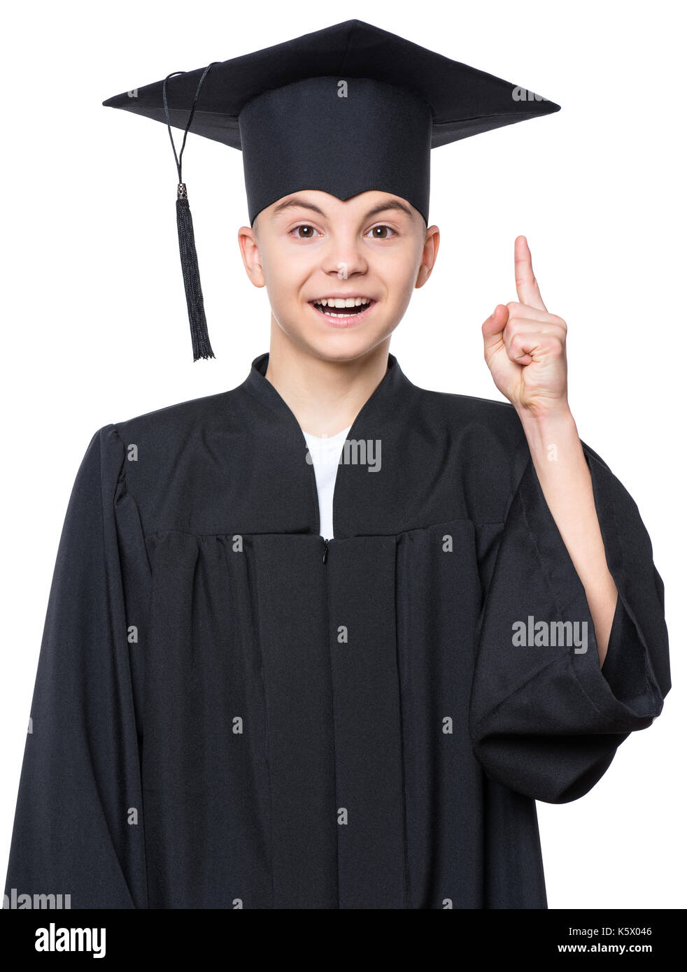 Portrait of graduate teen boy student in black graduation gown with hat ...