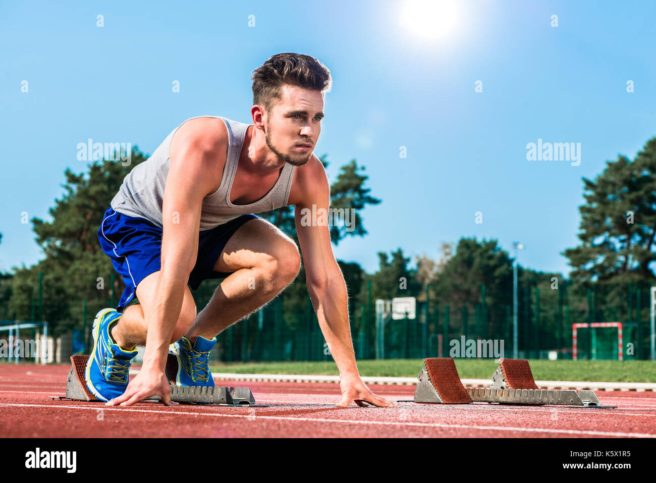 Track and field sprinter on starting point at cinder track in sports ...