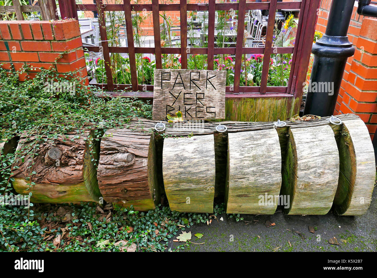 Bicycle park made from old tree with carved sign saying ''park yer bike ...