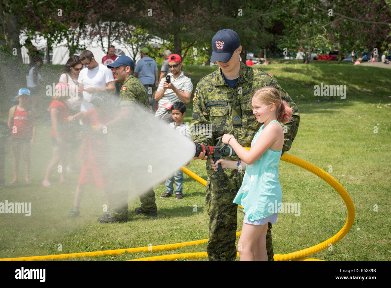 A young girl gets to use a fire hose with help from a Military Fire ...