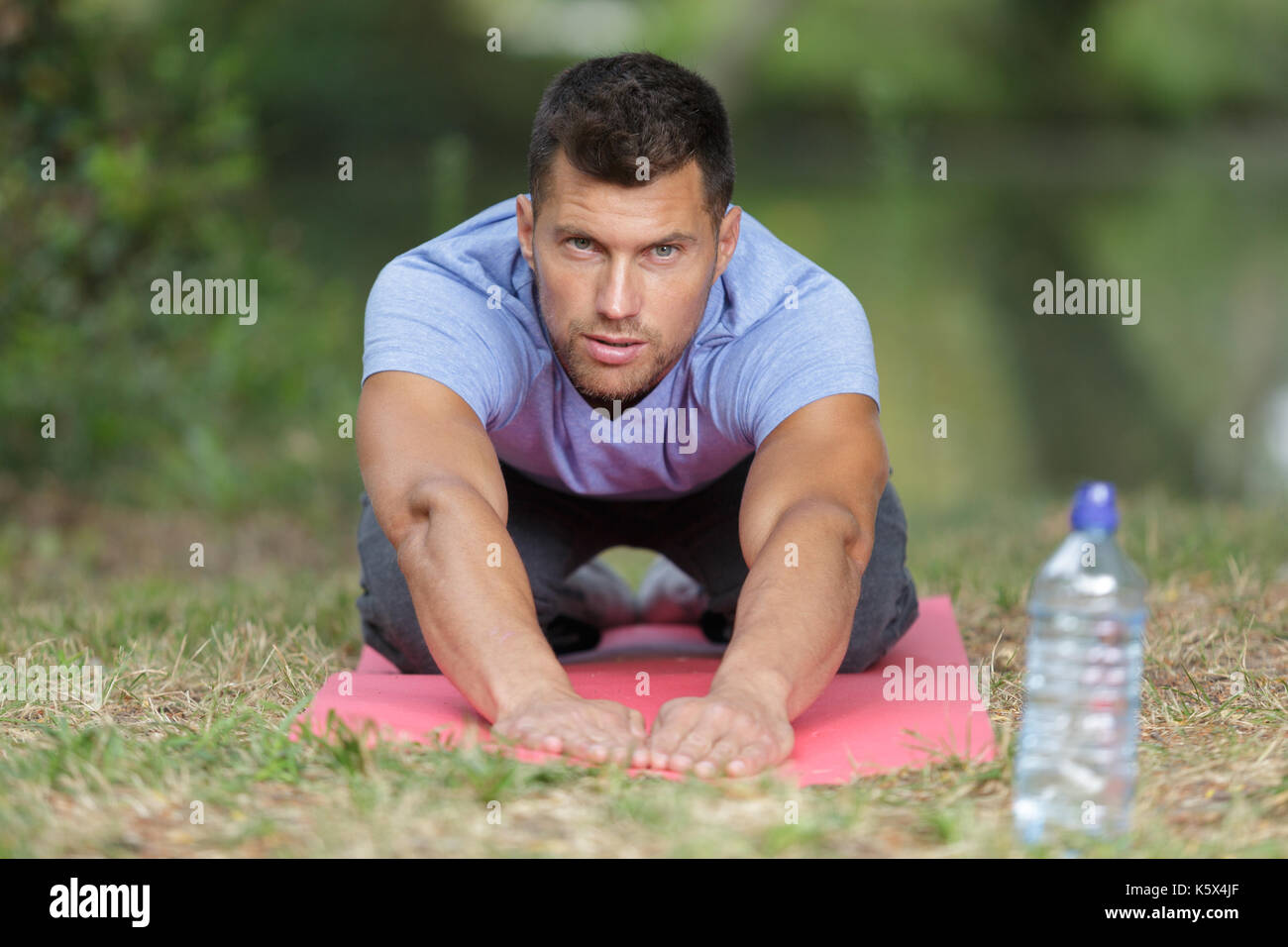 man stretching out muscles on matress in park Stock Photo - Alamy