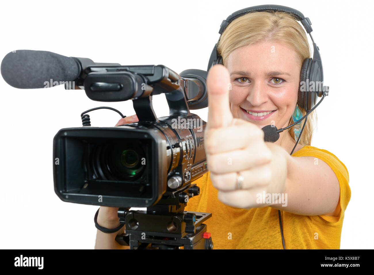 a blond young woman with professional video camera, showing thumb up ...