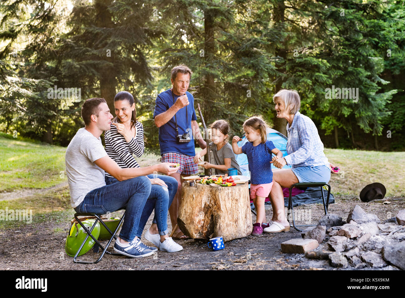 Beautiful family camping in forest, eating together Stock Photo - Alamy