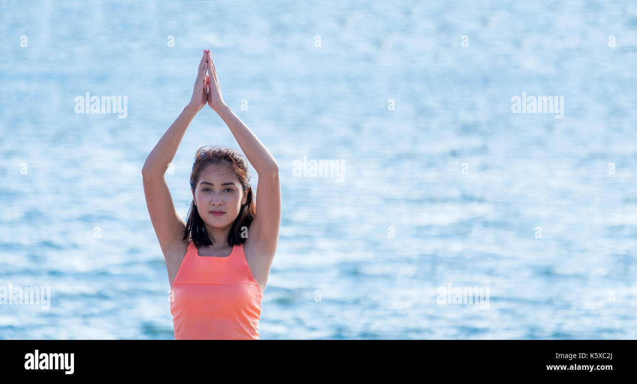 Close up female master yoga doing tress pose at beach and blue sea ...