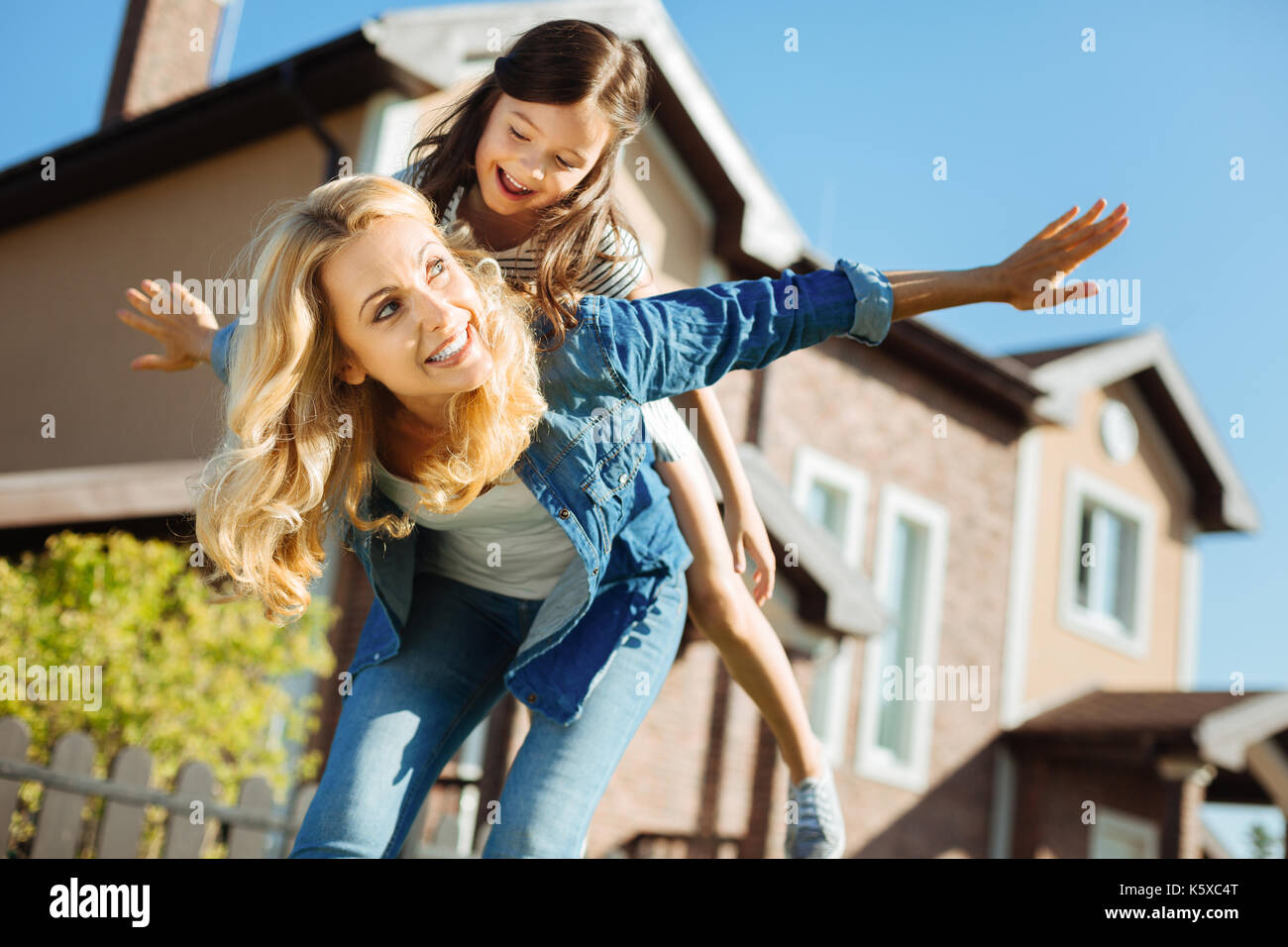 Happy mother carrying her daughter on back Stock Photo - Alamy