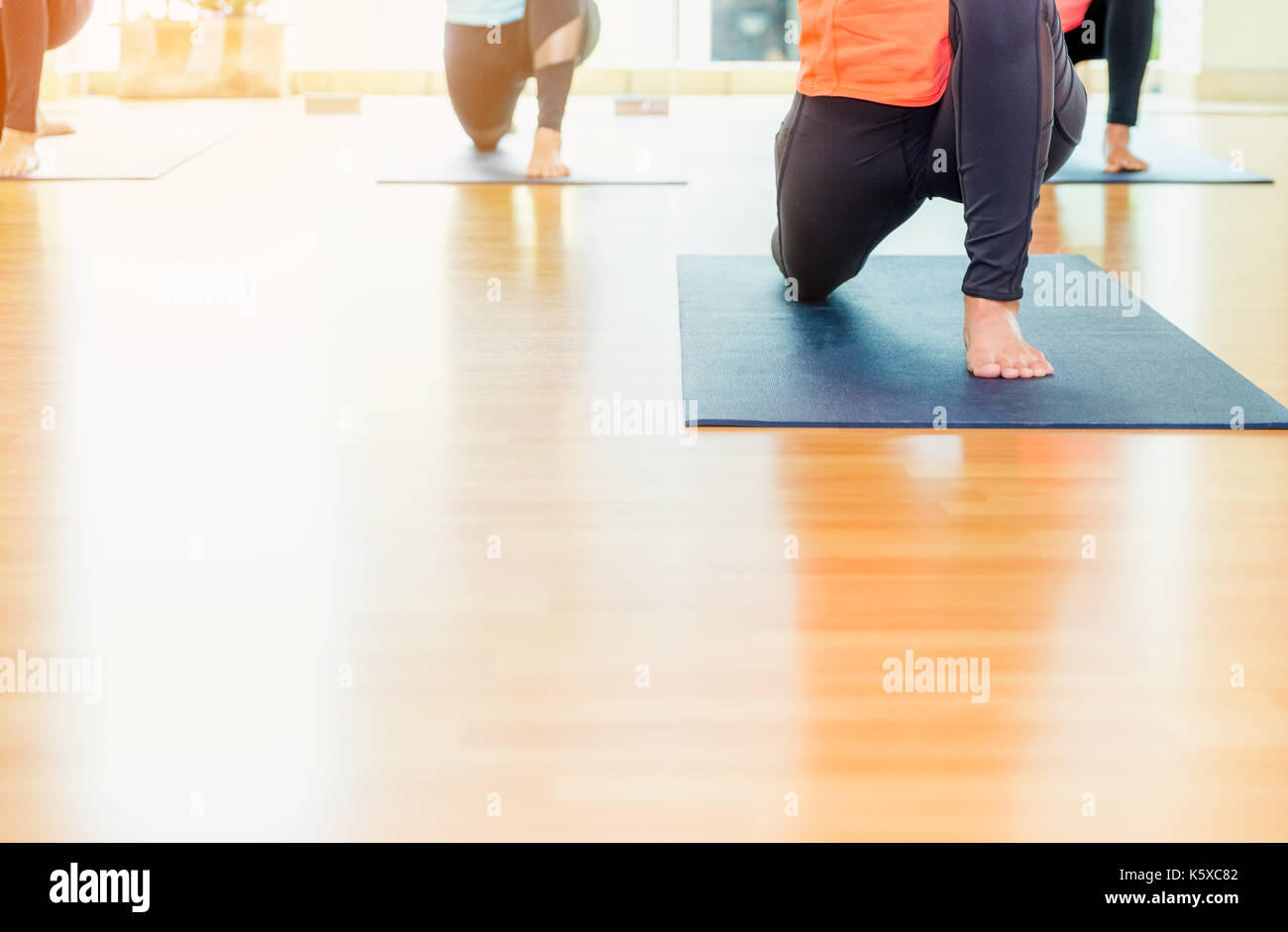 Close up feet of yoga class stretching on mat at studio classroom ...