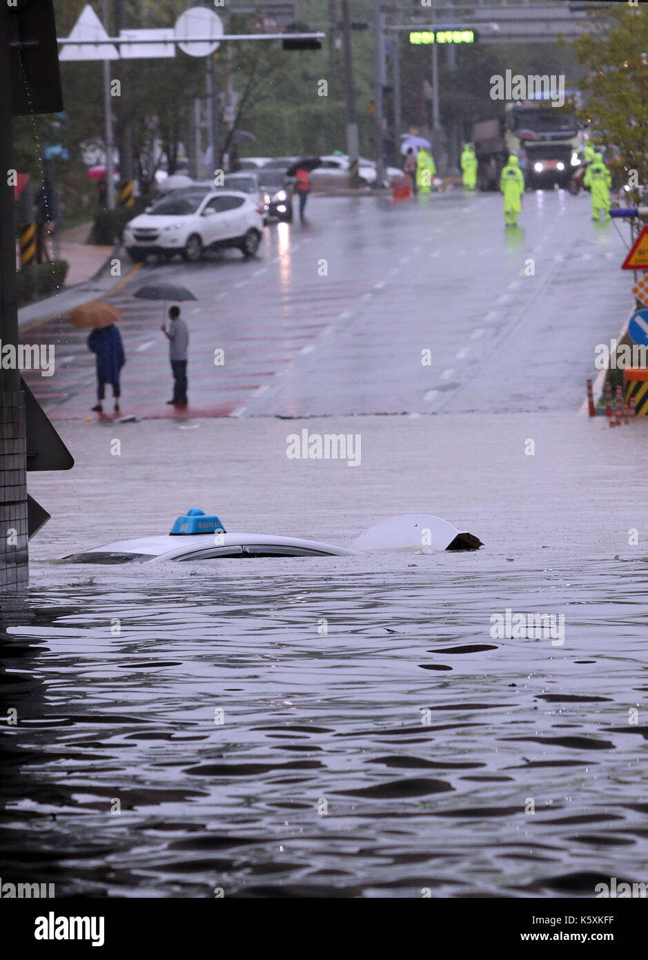 Flooded roads in Busan A taxi is inundated by flood water on a road in ...