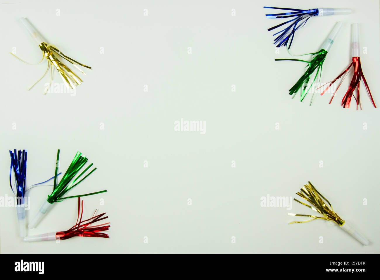 Red, green, gold and blue party noise makers with streamers on white ...
