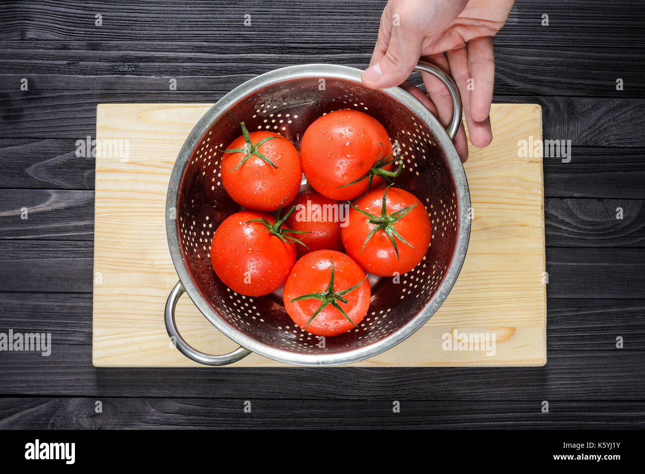 Wet Tomatoes in a Colander After Washing in Human Hand on Black Wooden ...