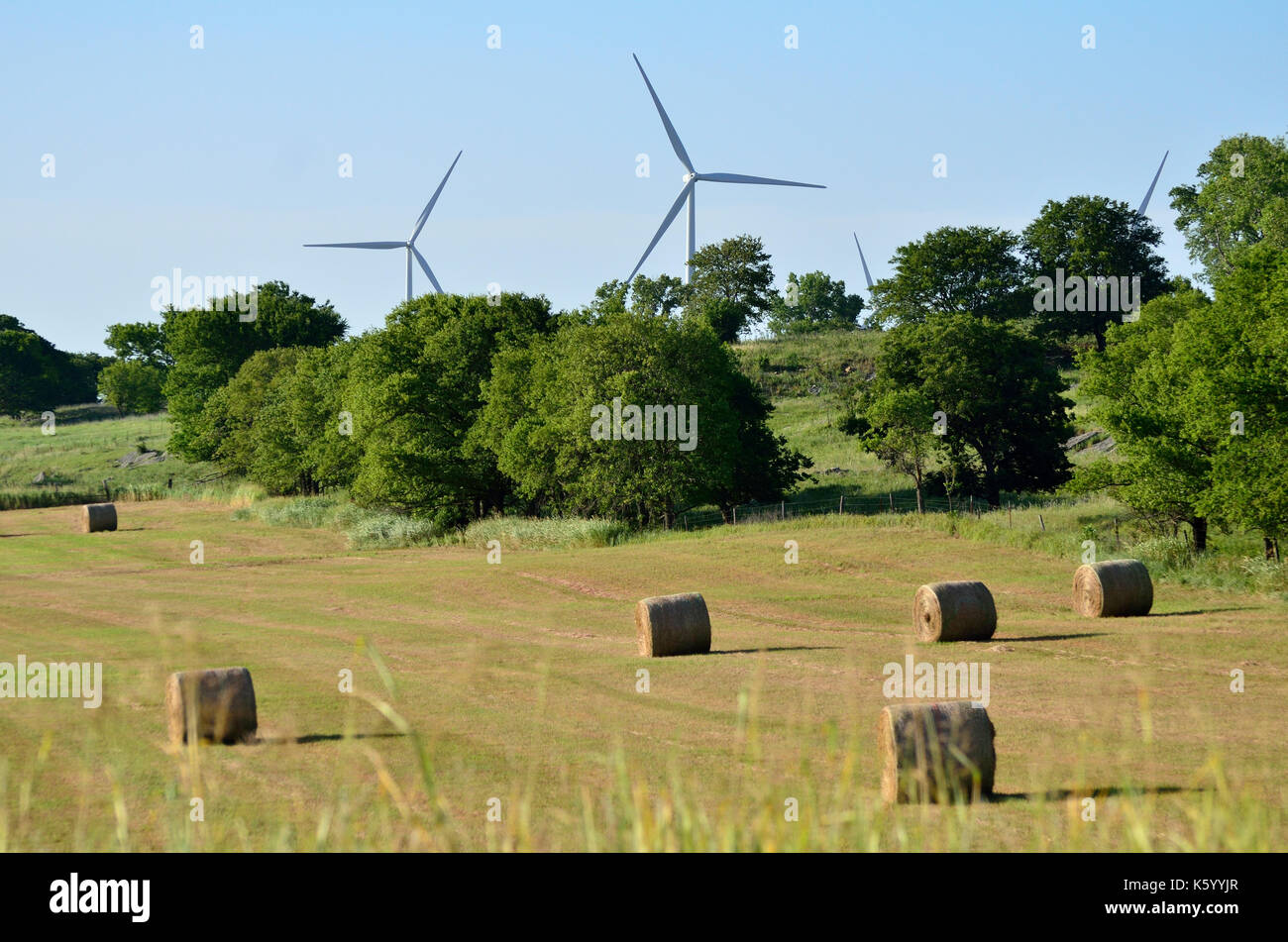 Wind turbines on hill overlooking round hay bales in an Oklahoma field ...