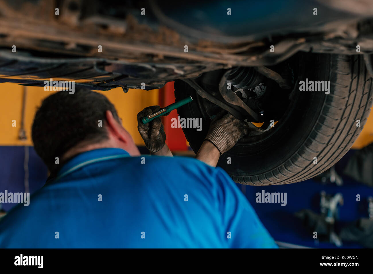 Mechanic repairs the car from below and shows the driver Stock Photo ...