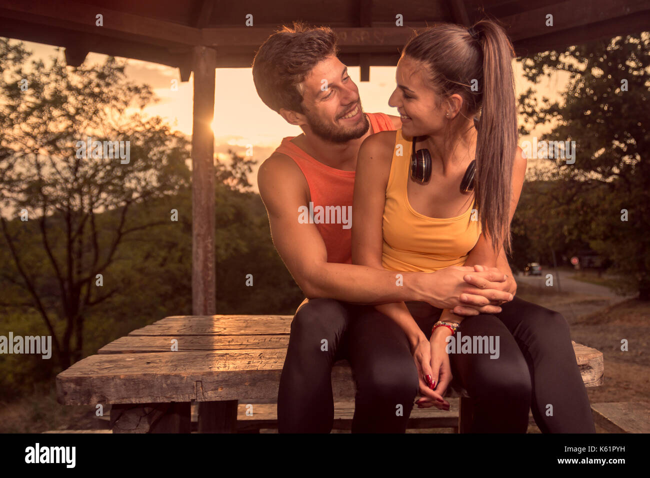 two young people, man woman couple, sitting together, hugging wood ...