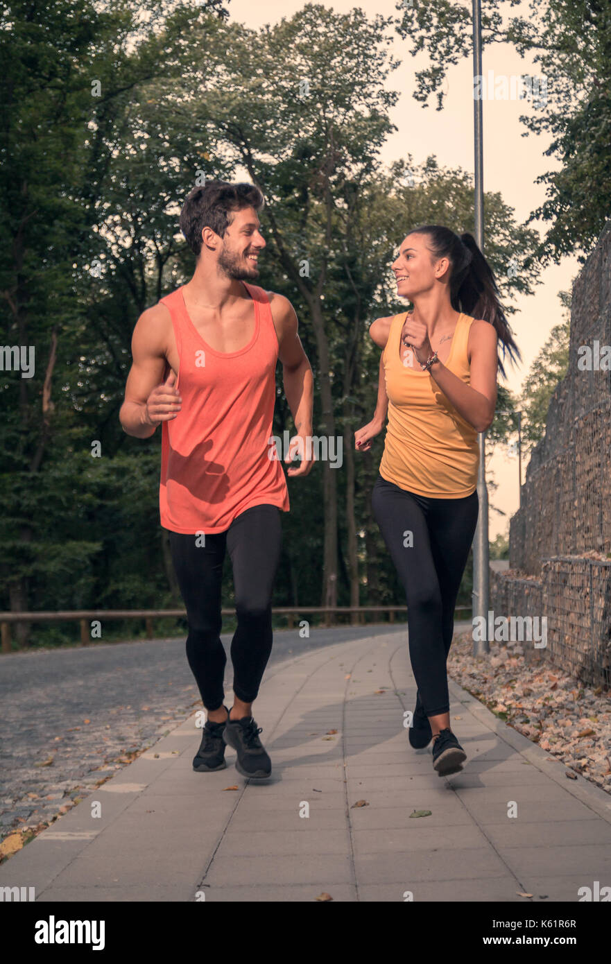 two young adult people, jogging, outdoors nature forest asphalt, sport ...