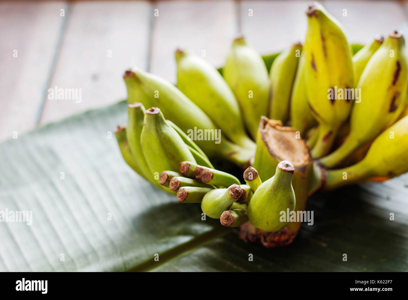 The small banana incomplete on the leaves Stock Photo - Alamy