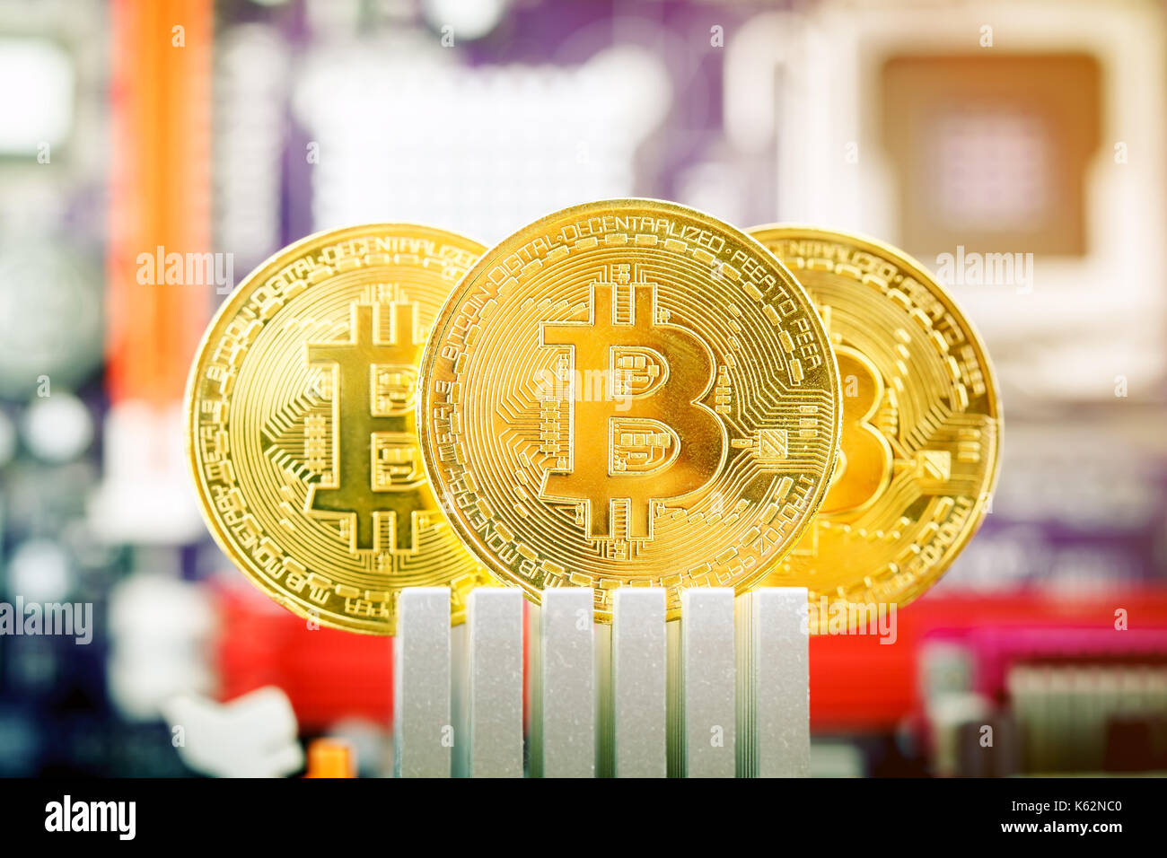 Three gold coins of bitcoin against the background of the motherboard ...