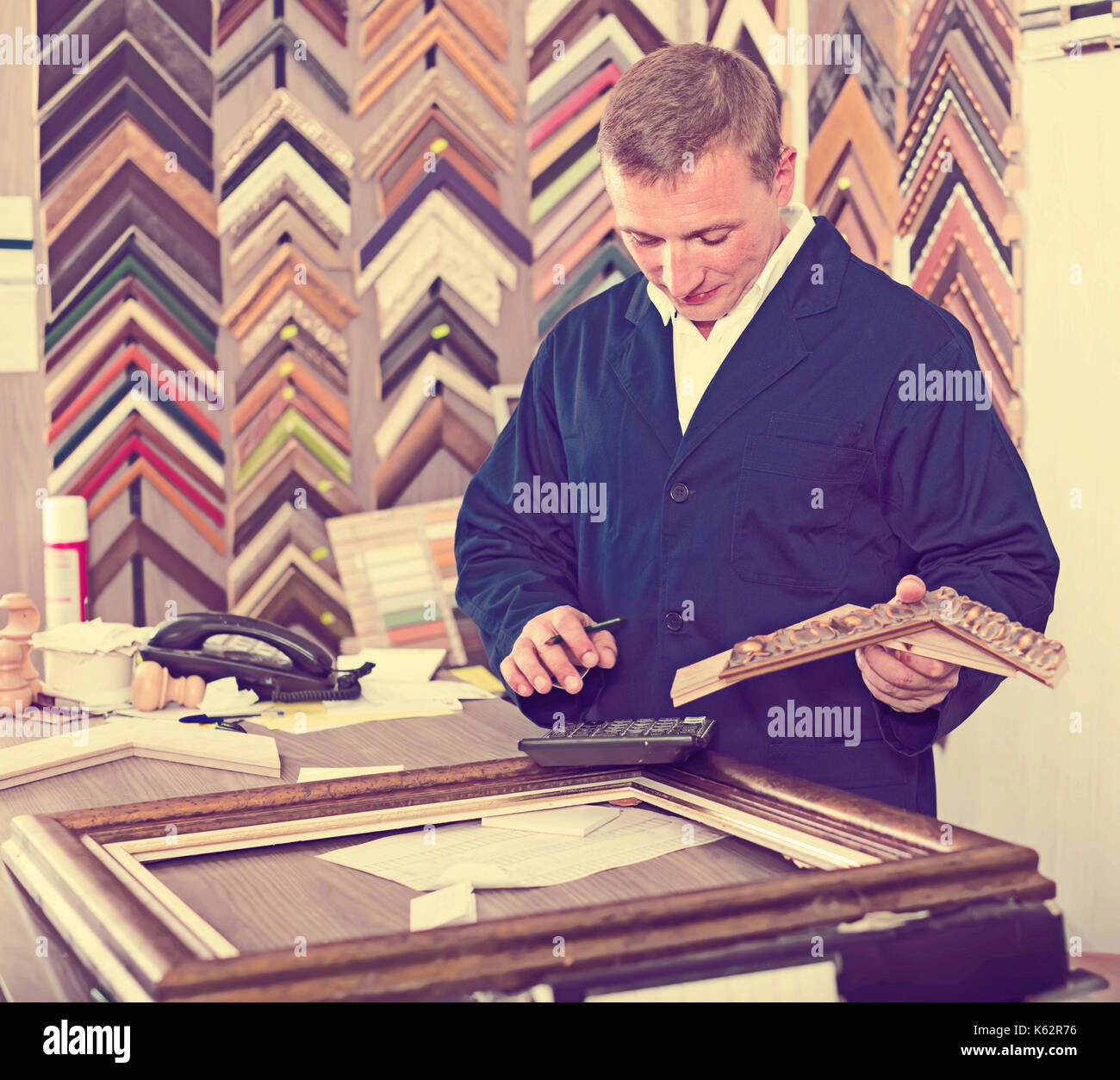 male seller standing in picture framing studio with wooden details ...