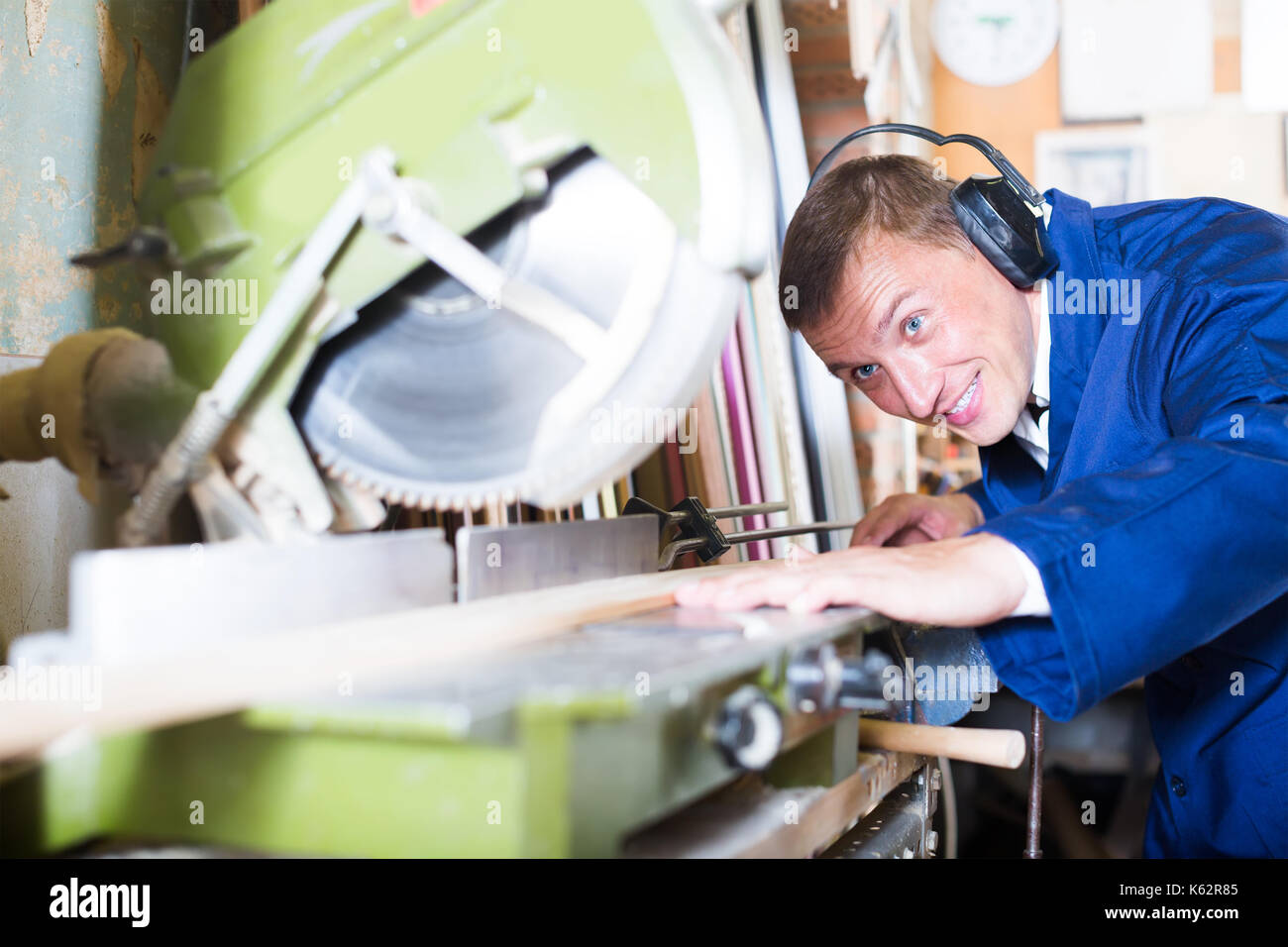vigorous workman cutting wooden planks using circular saw in workshop ...