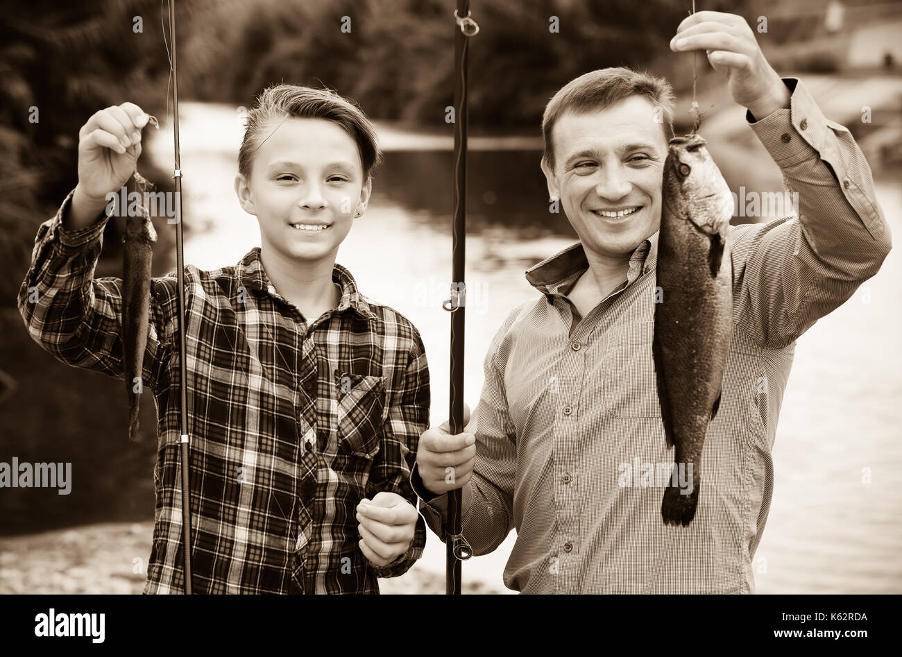 Happy teenage boy and his father holding fish on hook in hands Stock ...