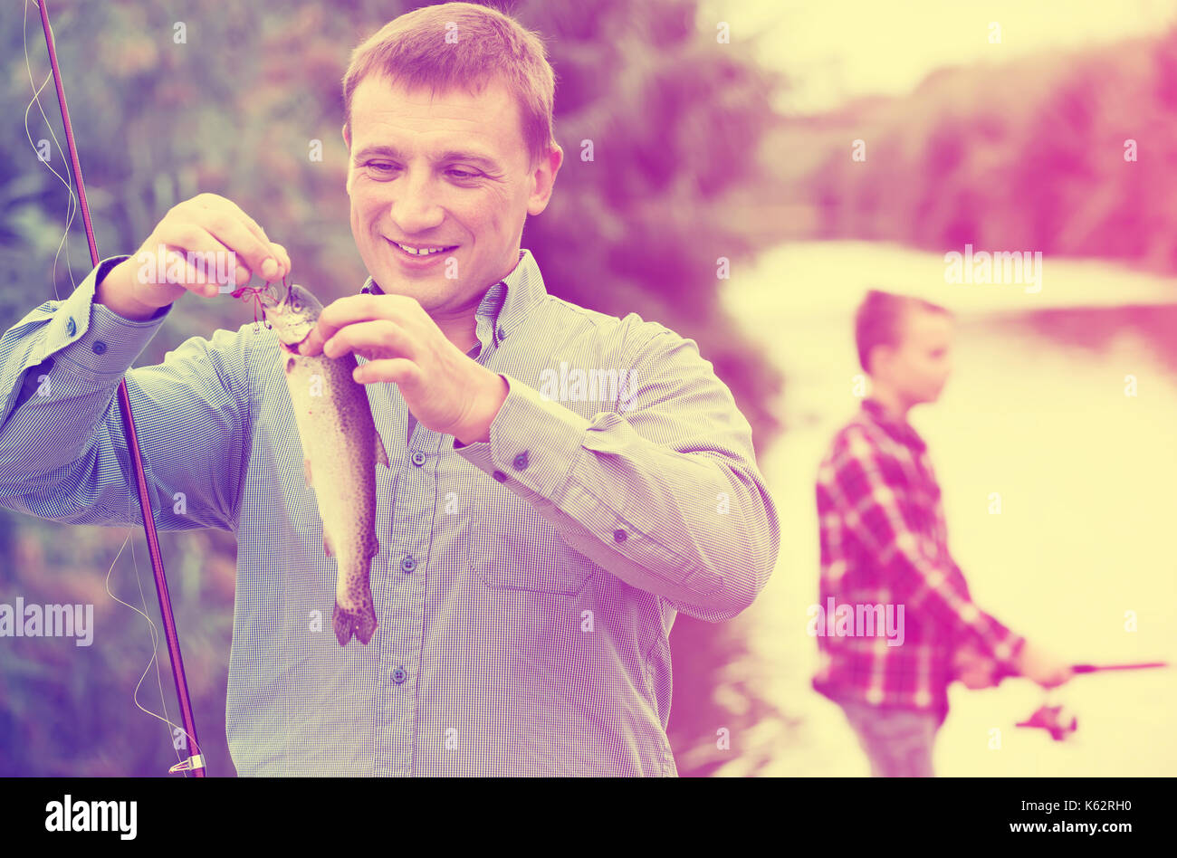 Glad man holding catch fish on hook in hands outdoors Stock Photo - Alamy