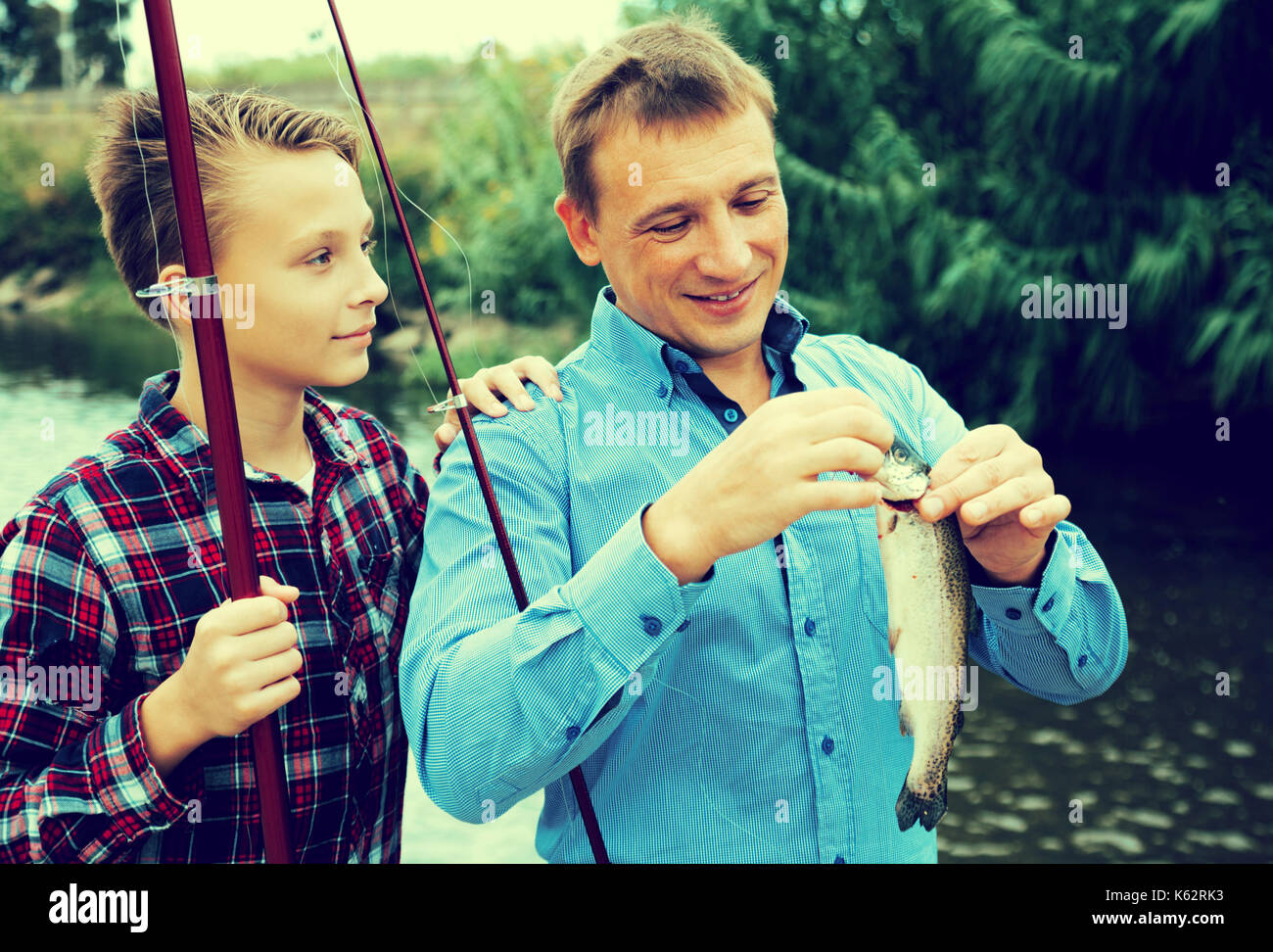 Portrait man with teenager boy releasing fish from hook outdoors Stock ...
