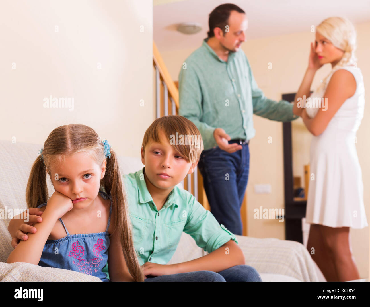 Unhappy young siblings waiting when parents stop screaming indoors ...