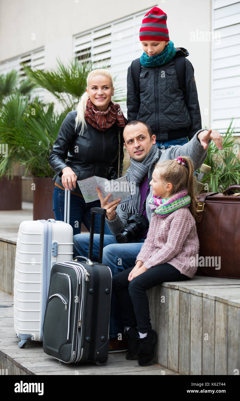 Happy middle class family of four checking direction in the map outdoor ...