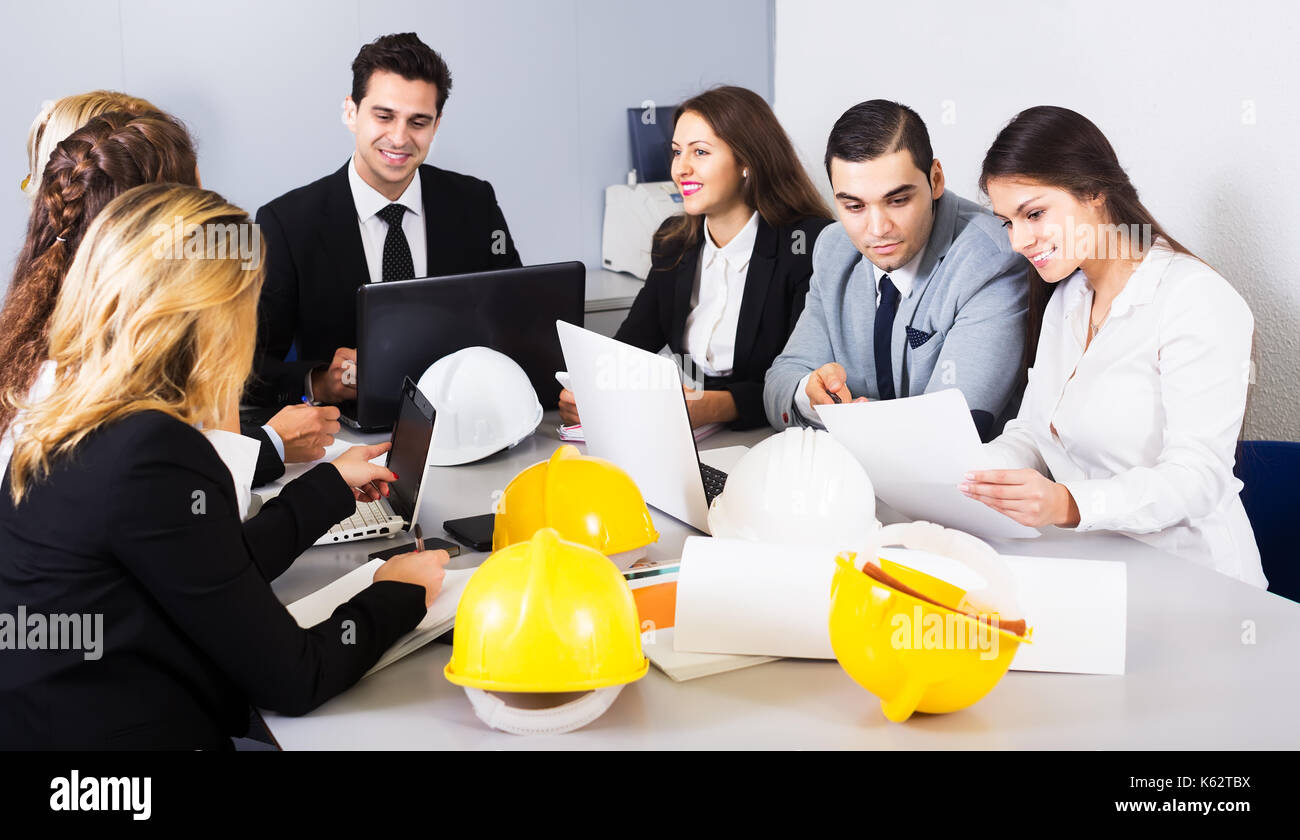 Team of positive professionals discussing business project and smiling ...