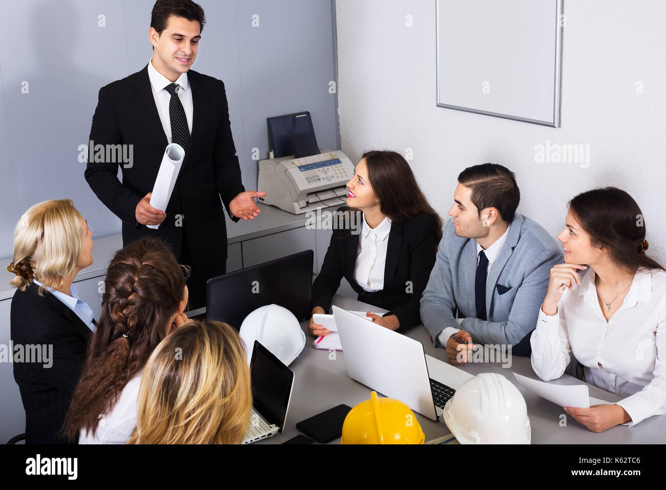 Team of smiling engineers discussing business project in office ...