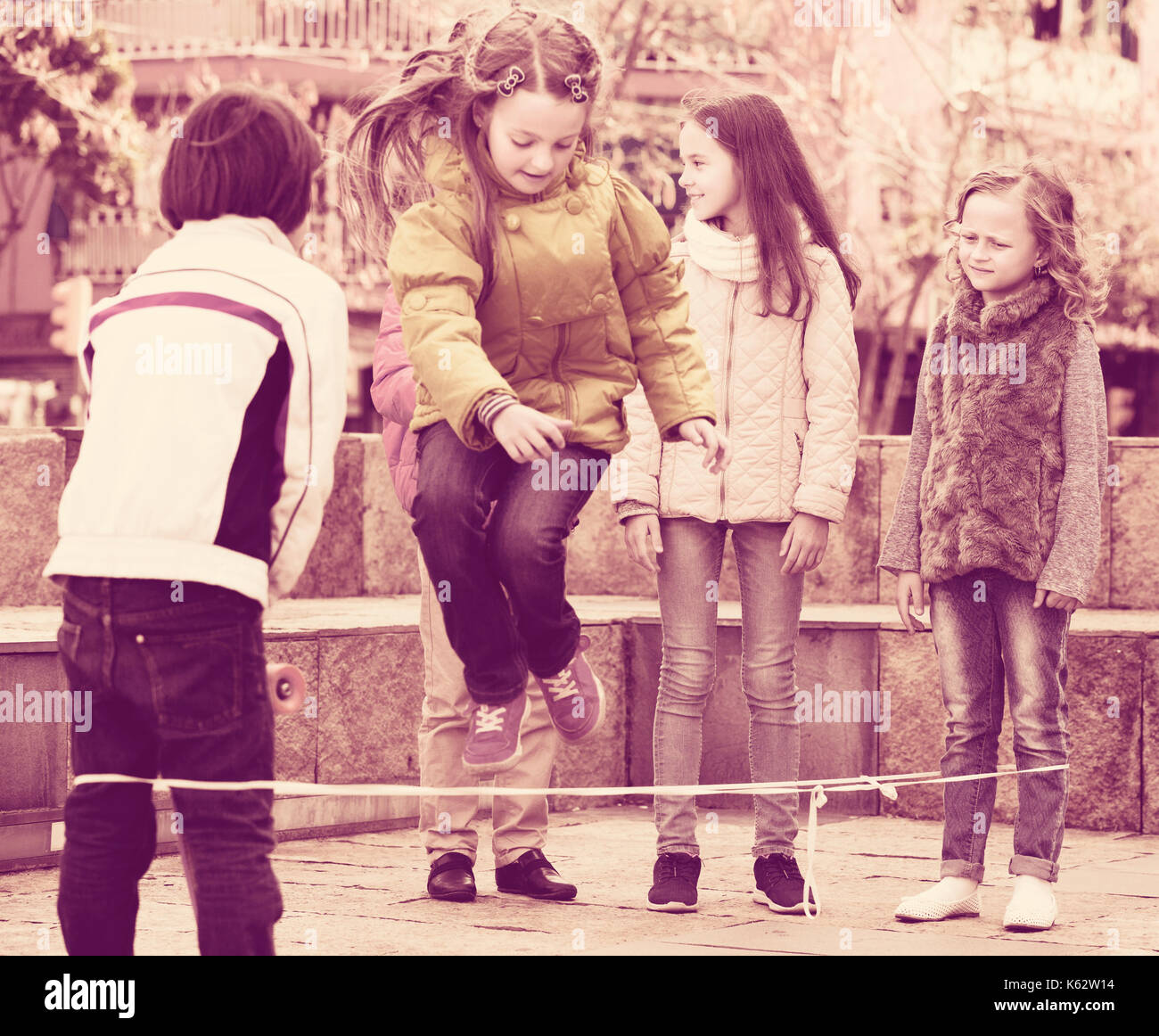 Active children playing rubber band jumping game and laughing outdoors ...