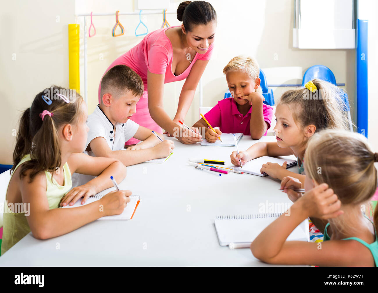 happy european children making writing exercises with help of teacher ...