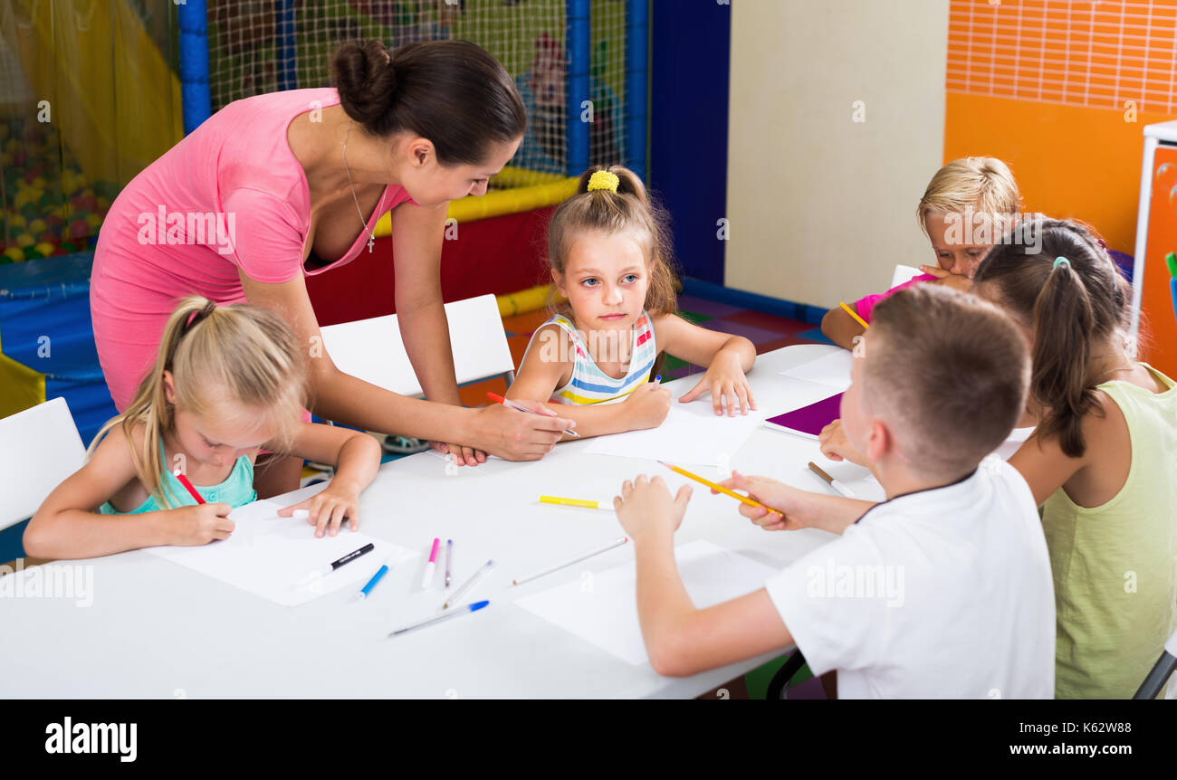 Glad kids drawing on lesson in elementary school class with help of ...