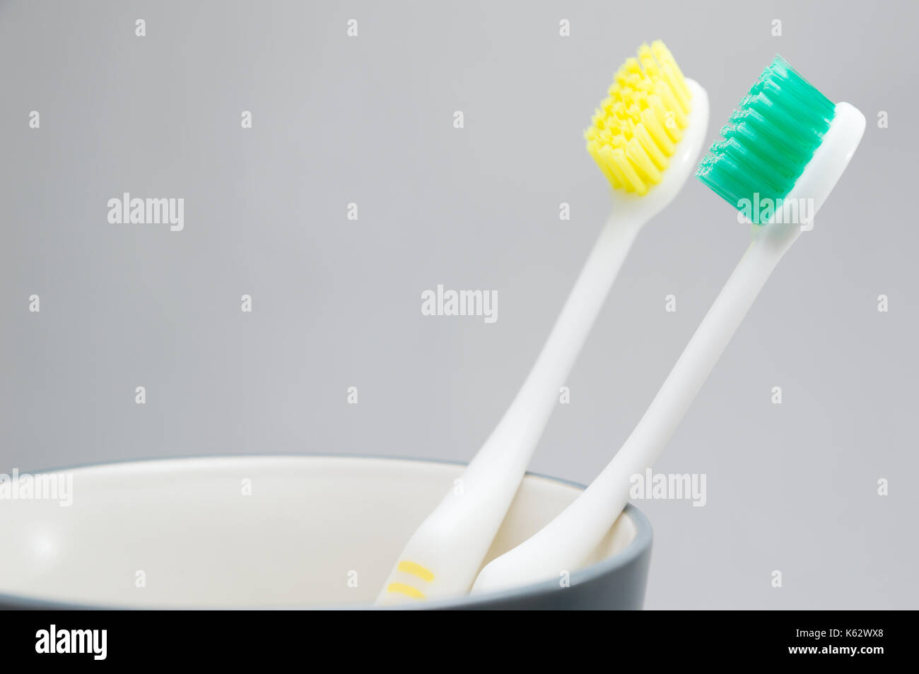 Toothbrushes in cup on white background Stock Photo - Alamy