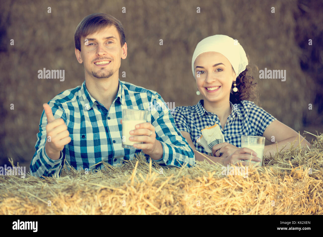 portrait of two young happy farmers taking a pause in the hay and ...