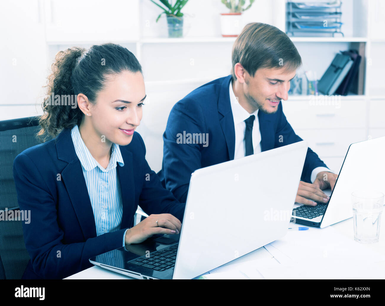 Man and young woman coworkers sitting and working on computers in firm ...