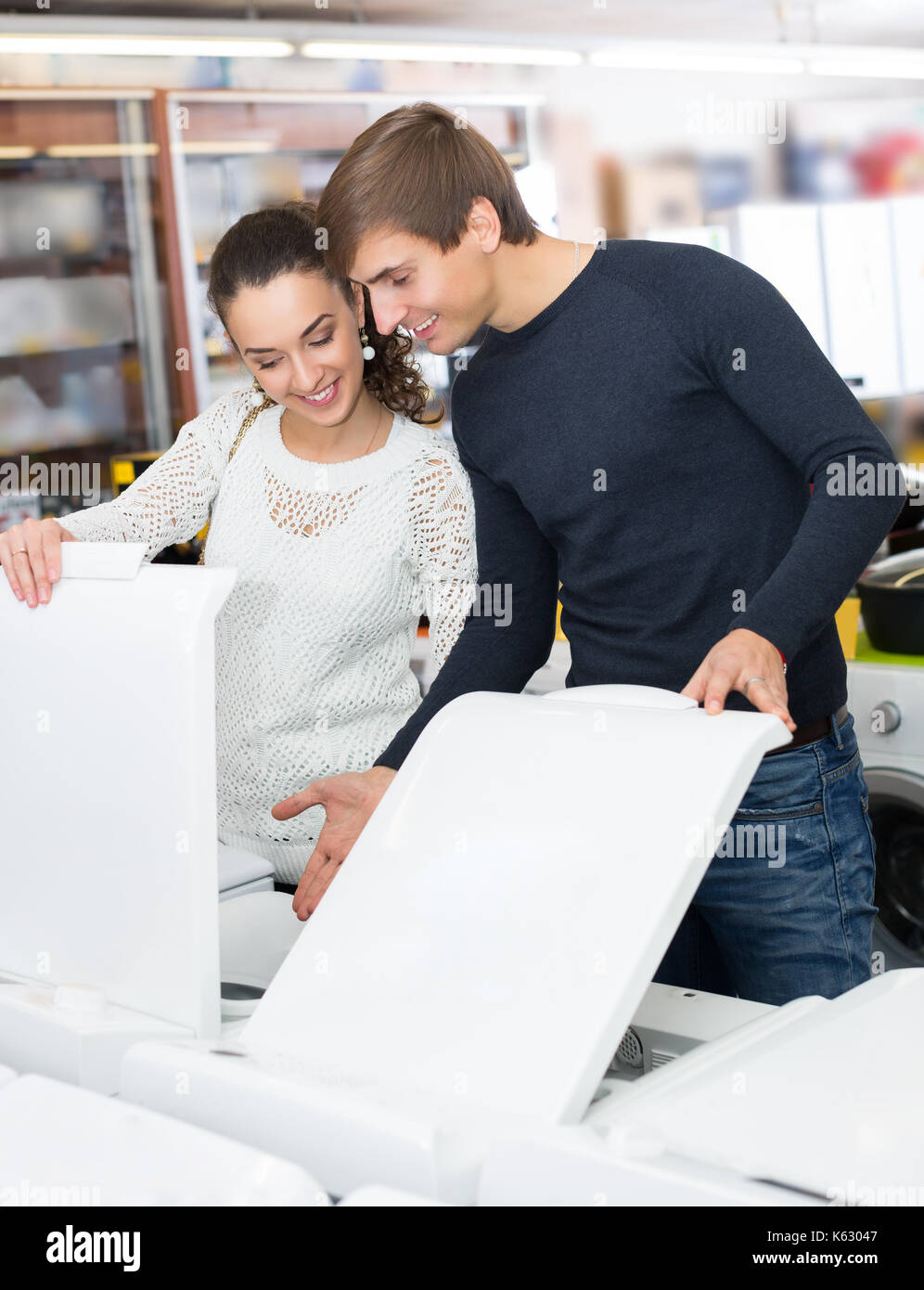 Happy family couple buying new clothes washer in appliance store Stock ...