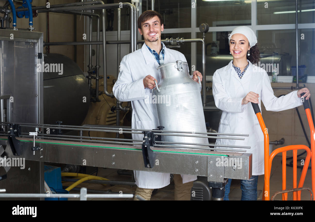 Young man and woman in the uniform bottling fresh milk on the ...