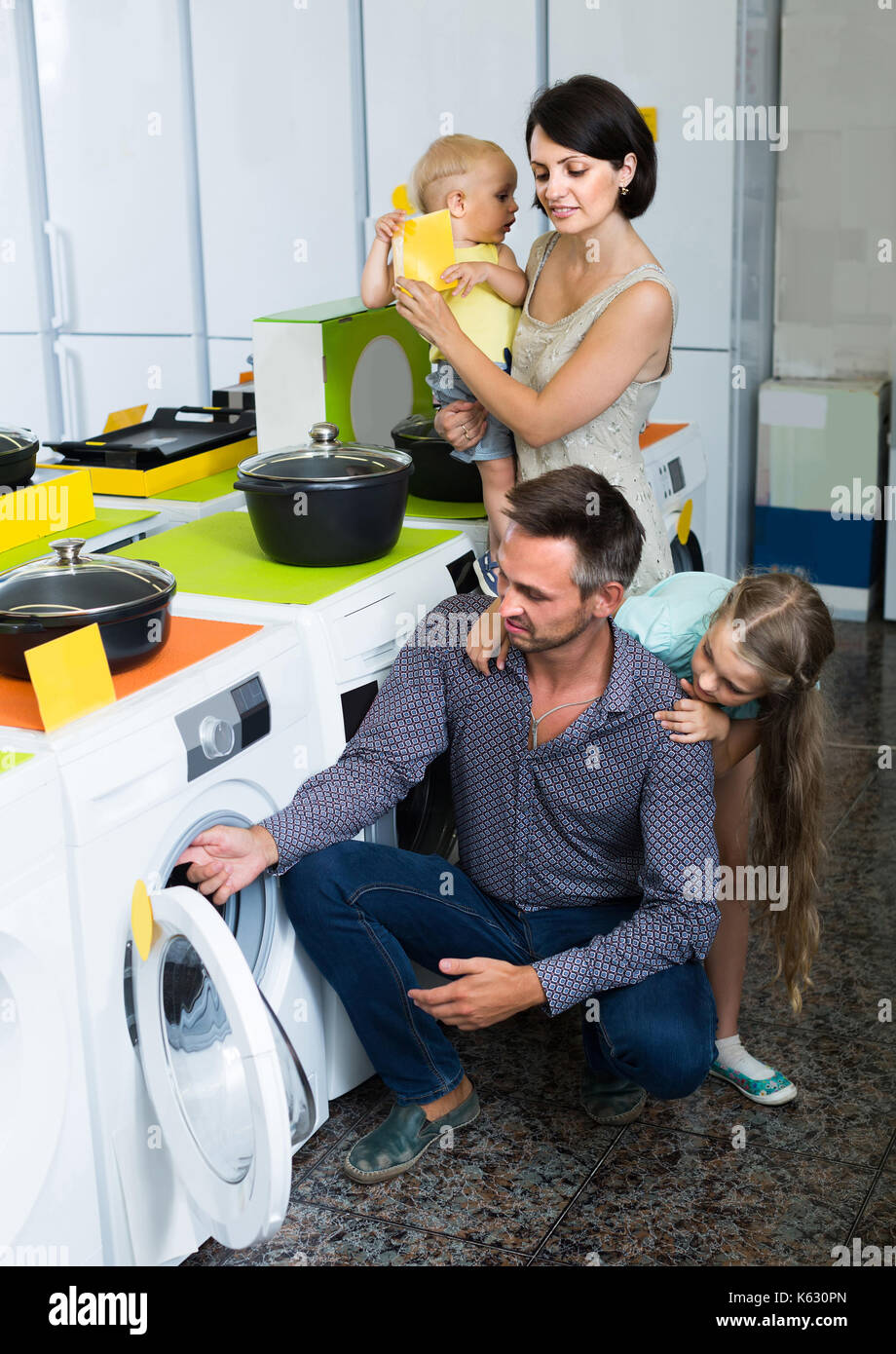 positive european parents with two kids choosing washing machine in ...