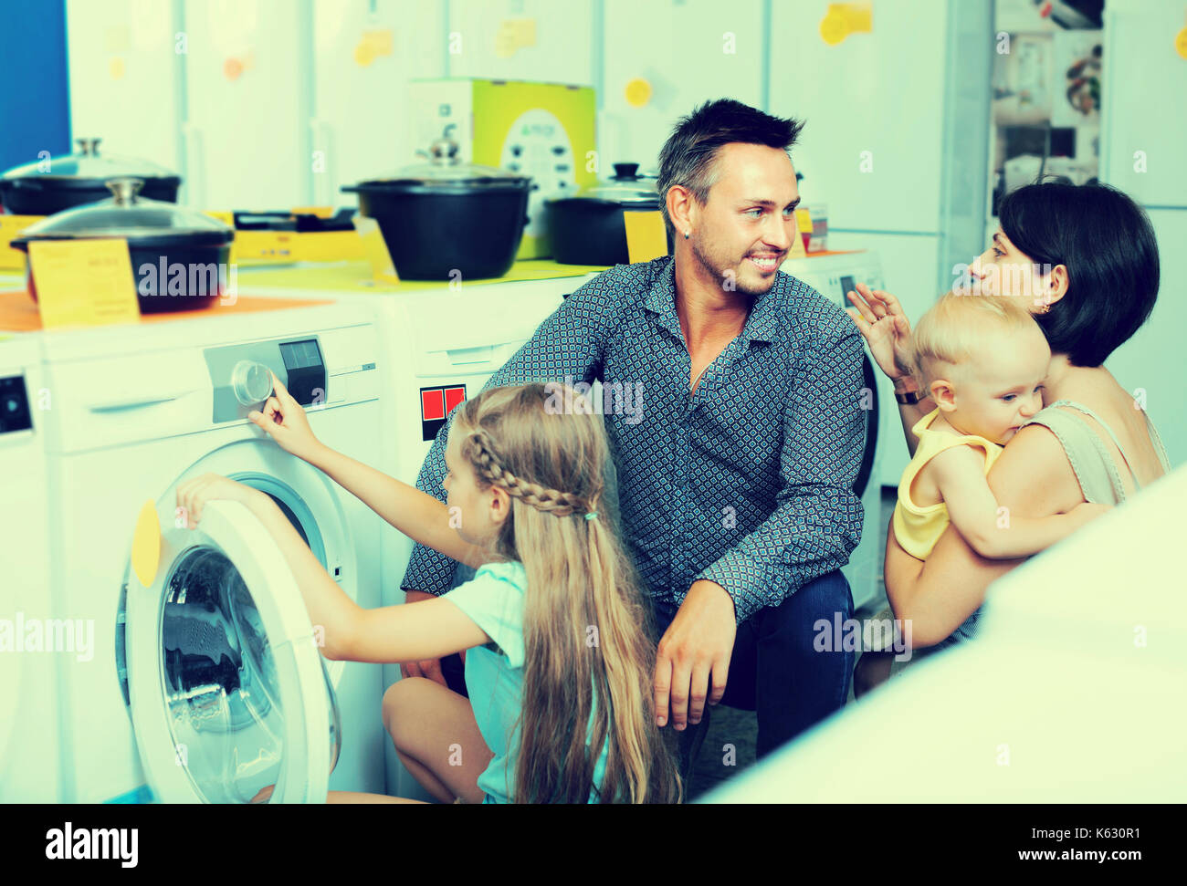 Happy family with kids choosing modern washing machine in appliances ...