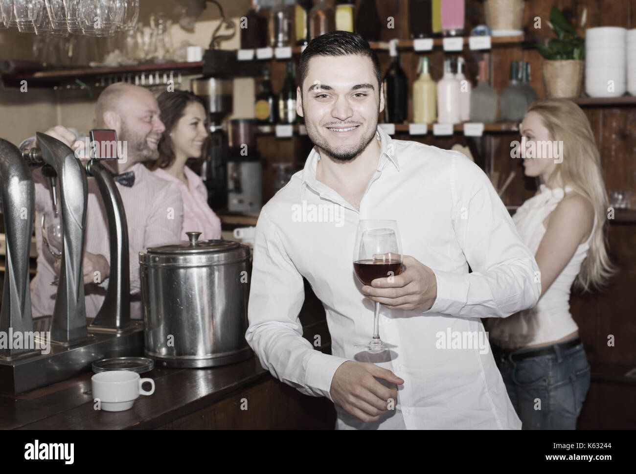 Portrait cheerful man waiting for table in restaurant and drinking wine ...