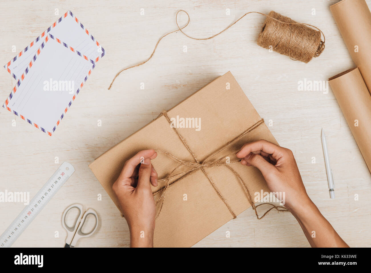 Man wrapping gift. A parcel wrapped in brown paper and tied with rough ...