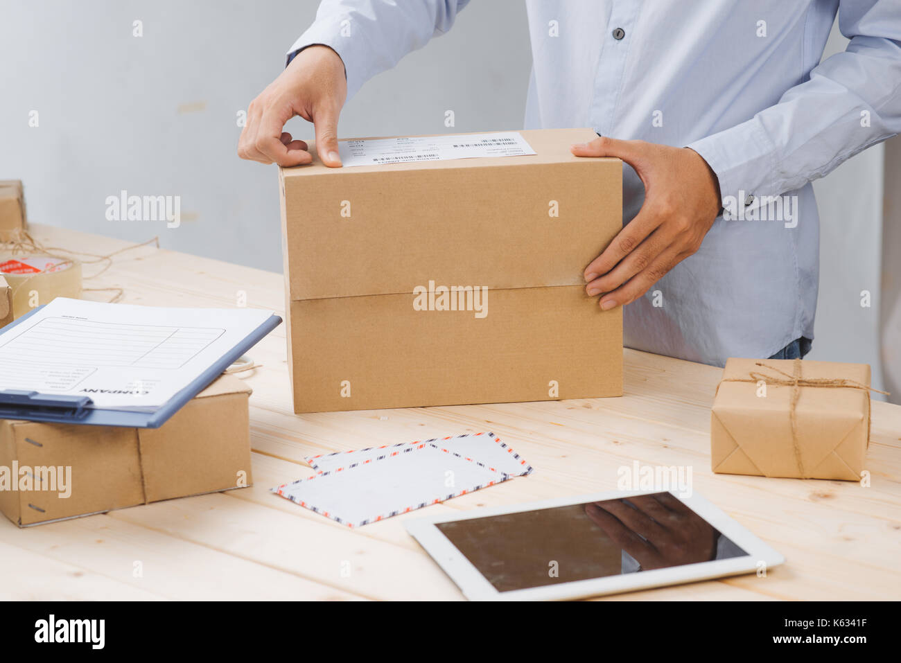 Deliveryman taping and packing cardboard box for delivery Stock Photo ...